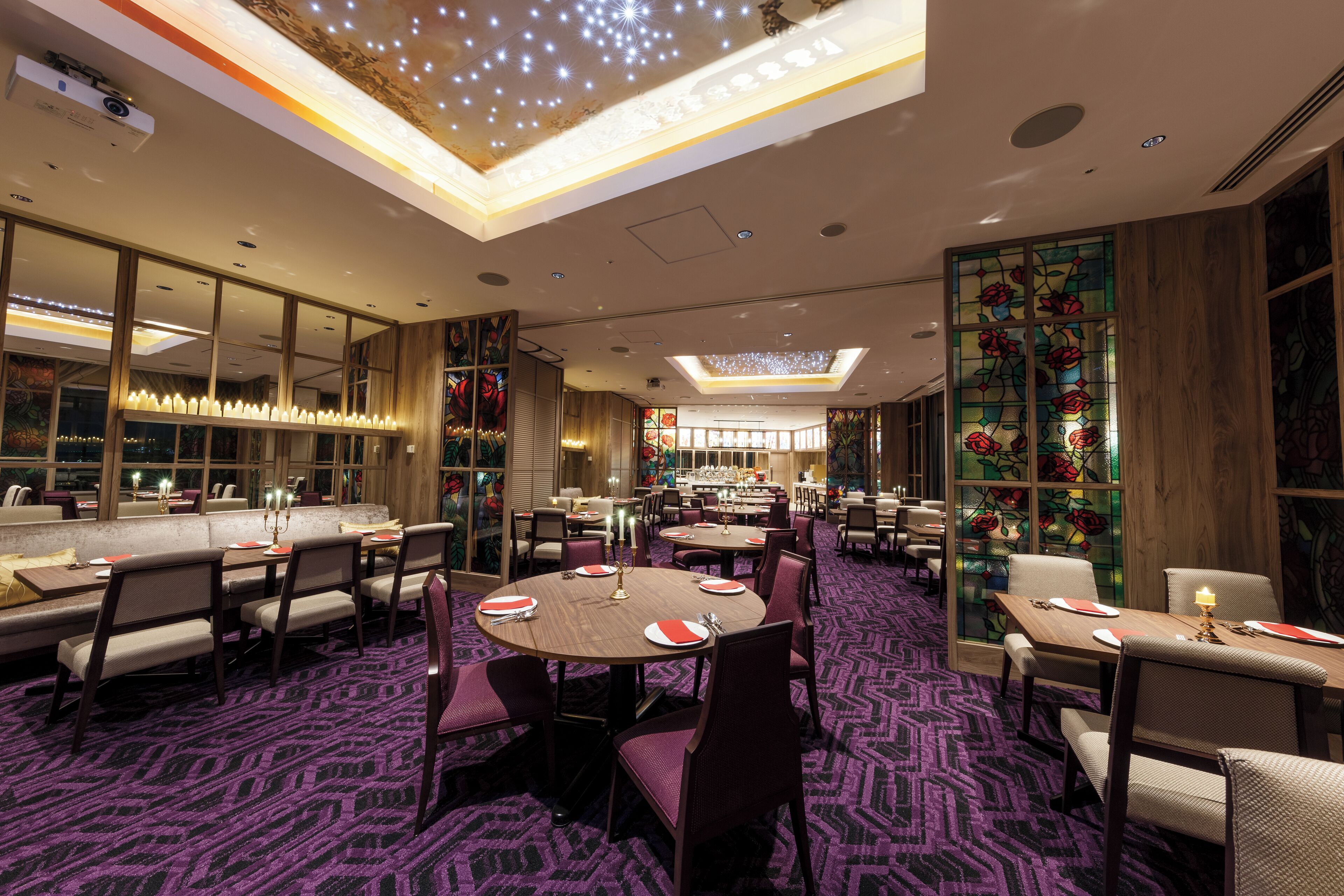 Uma sala de jantar de hotel com várias mesas redondas, cadeiras e um tapete estampado.