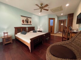 Quarto com cama grande, cabeceira de madeira, ventilador de teto e mesa de cabeceira com abajur.