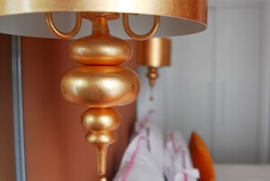 Um close-up de um abajur cor de cobre com cúpula branca.