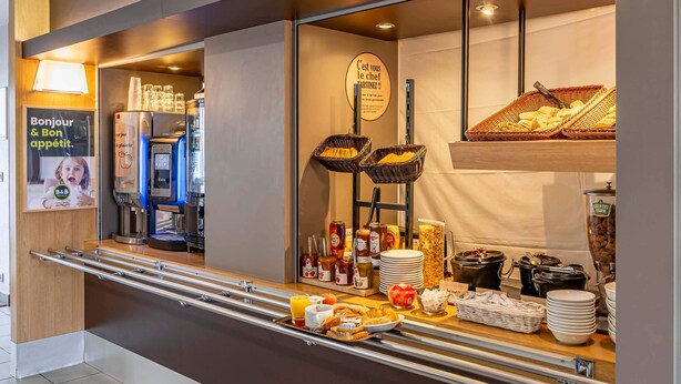 Um buffet de café da manhã com diversos alimentos, acompanhamentos e uma máquina de café.