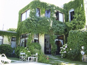 Uma casa com paredes cobertas de hera e um jardim com plantas e flores em vasos.