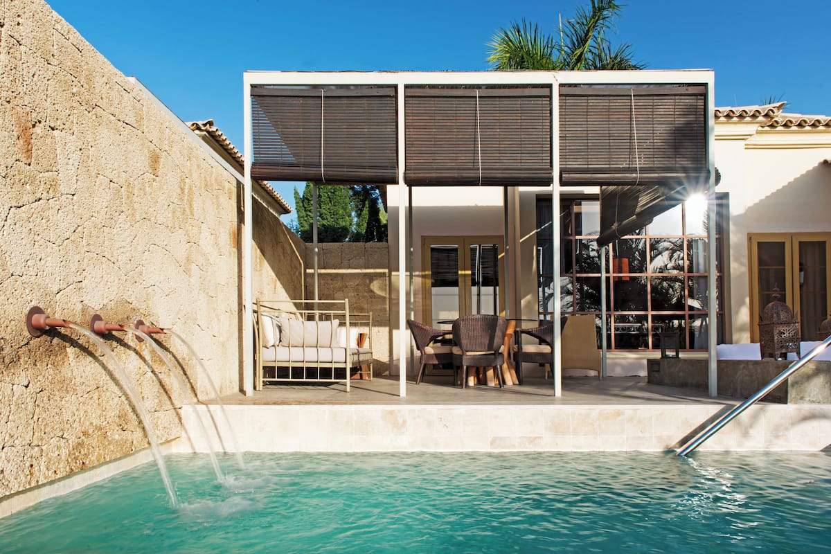 Uma área de piscina com espaço para sentar integrado e um muro de pedra.