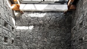 Um banheiro com paredes de pedra, um domo de vidro e pétalas de rosa no chão.