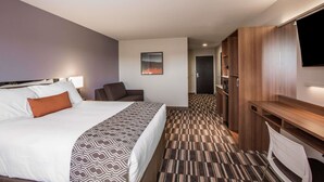 Quarto de hotel com uma cama grande, uma mesa, uma televisão e um guarda-roupa.