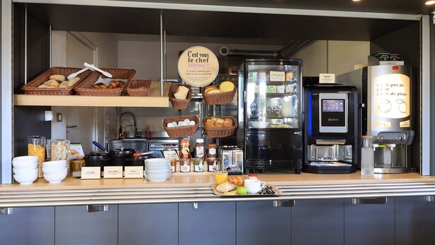 Um buffet de café da manhã com diversos alimentos e uma máquina de café.