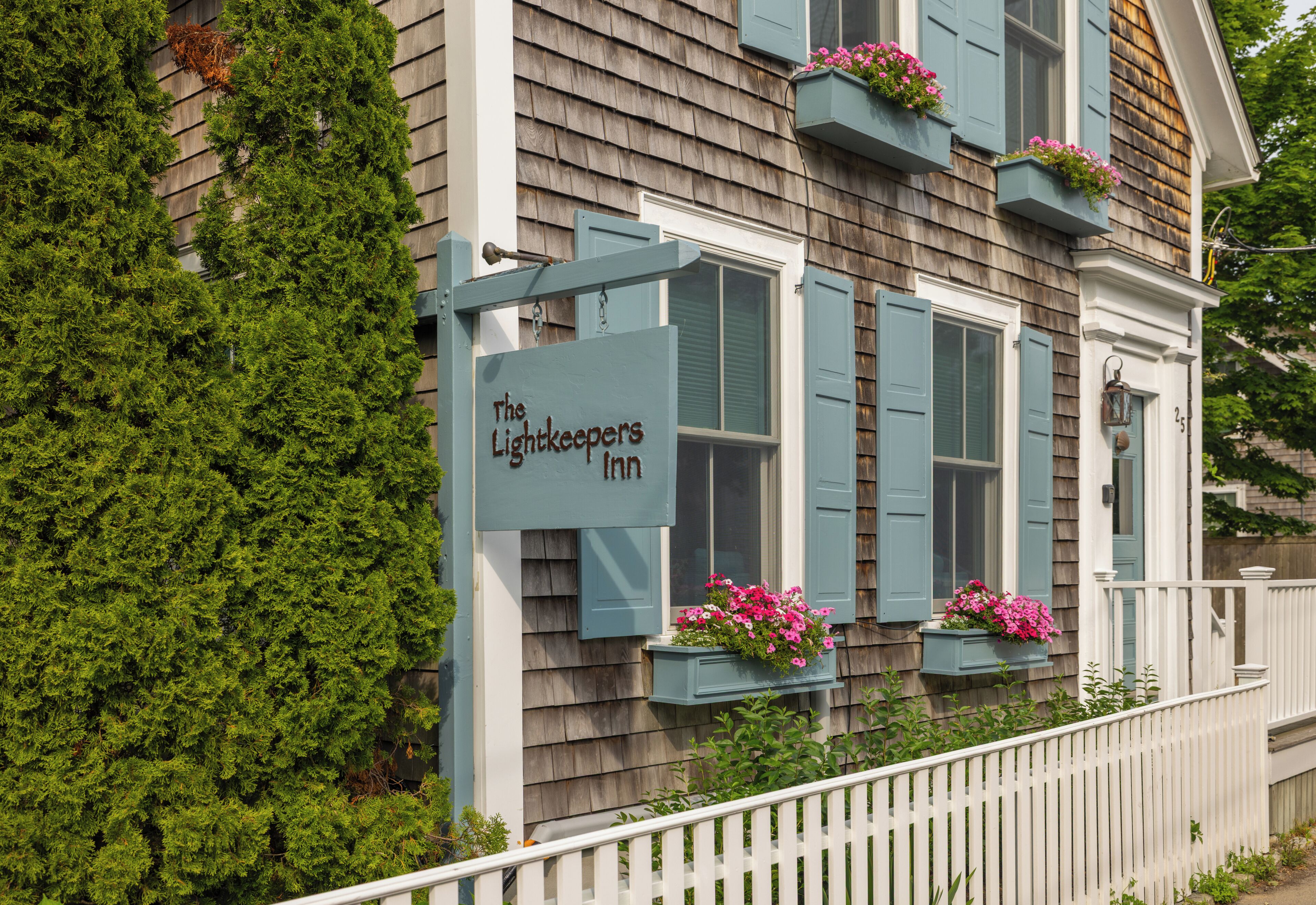 Um edifício com uma placa que diz 'The Lightkeepers Inn' e caixas de flores nas janelas.