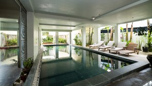 Piscina com espreguiçadeiras e plantas em vasos.