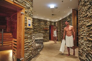 Área de spa com paredes de pedra, bancos de madeira e uma porta de madeira com a inscrição 'Bio Sauna'.