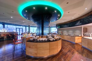 Um lobby de hotel moderno com um balcão central em formato de ilha, piso de madeira e teto com um design espiral único.