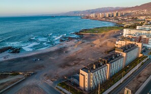 Paisagem costeira com praia, edifícios altos e vista clara do oceano.