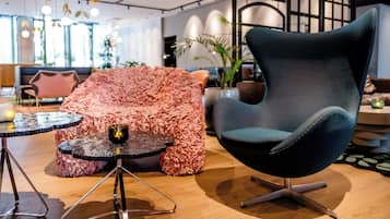 Uma área de estar moderna com um sofá rosa exclusivo, uma poltrona azul escura e uma mesa de centro de vidro.