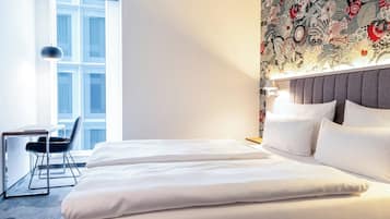 Quarto de hotel com uma cama, uma escrivaninha e uma cadeira.