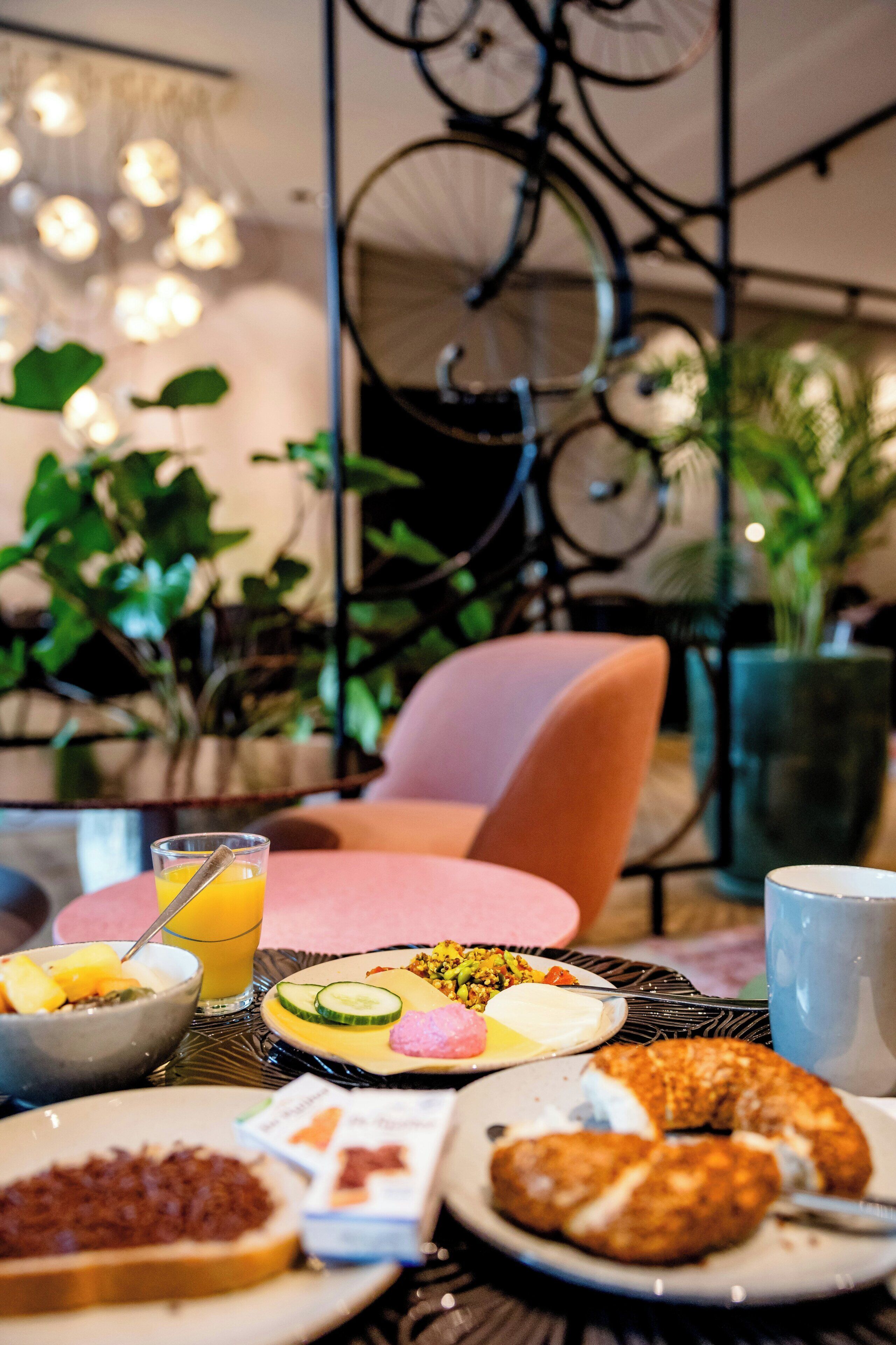 Uma mesa de café da manhã com diversos alimentos, incluindo um prato com ovos, uma tigela de cereal e um copo de suco de laranja.