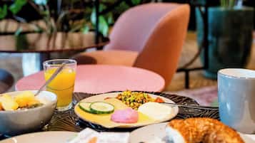 Uma mesa de café da manhã com diversos alimentos, incluindo um prato com ovos, uma tigela de cereal e um copo de suco de laranja.
