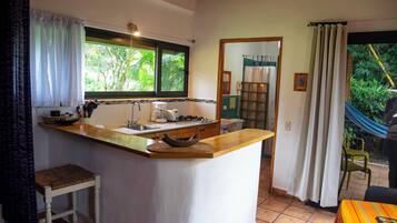 Uma cozinha compacta com uma ilha central, uma pia e uma janela com cortinas.