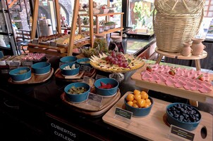 Buffet com diversas opções de comida, incluindo frutas, queijos e carnes.