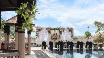 Uma área à beira da piscina com um gazebo, um espaço de estar coberto e um painel de flores.