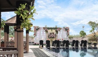 Uma área à beira da piscina com um gazebo, um espaço de estar coberto e um painel de flores.