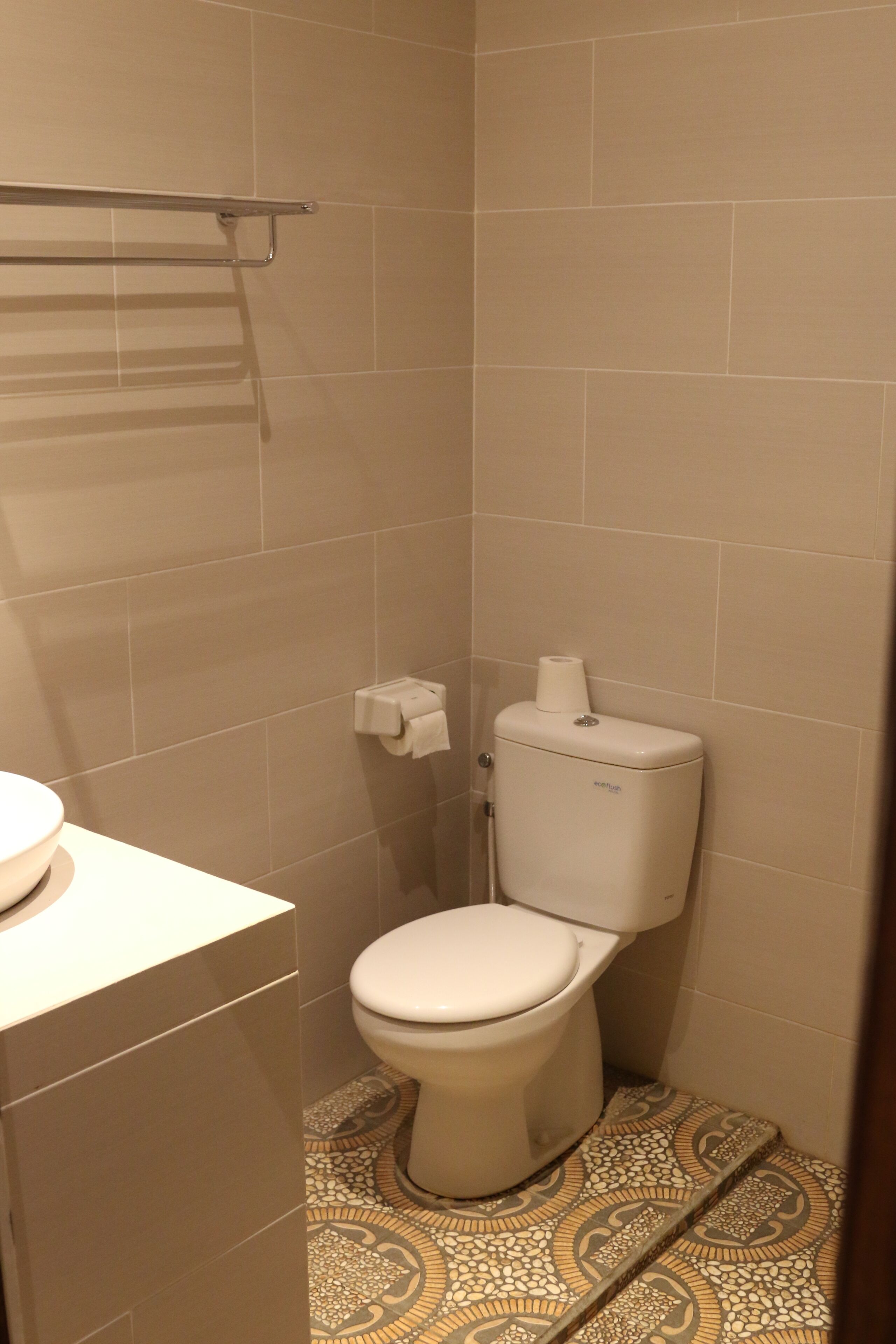 Um banheiro pequeno com azulejos, vaso sanitário, pia e porta-toalhas.