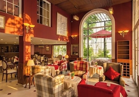 A spacious indoor area with multiple seating arrangements, including sofas and chairs, and a large arched window providing natural light.