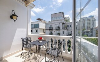 Varanda com mesa e cadeiras, um vaso de planta e vista para edifícios.