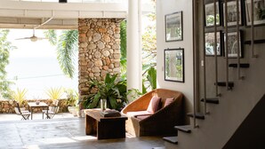 Um quarto com parede de pedra, móveis de vime e quadros nas paredes.