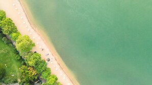 Vista aérea de uma praia com guarda-sóis e pessoas.