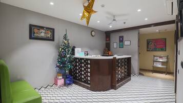 Uma área de recepção com um pinheiro de Natal, um quadro emoldurado e um relógio na parede.