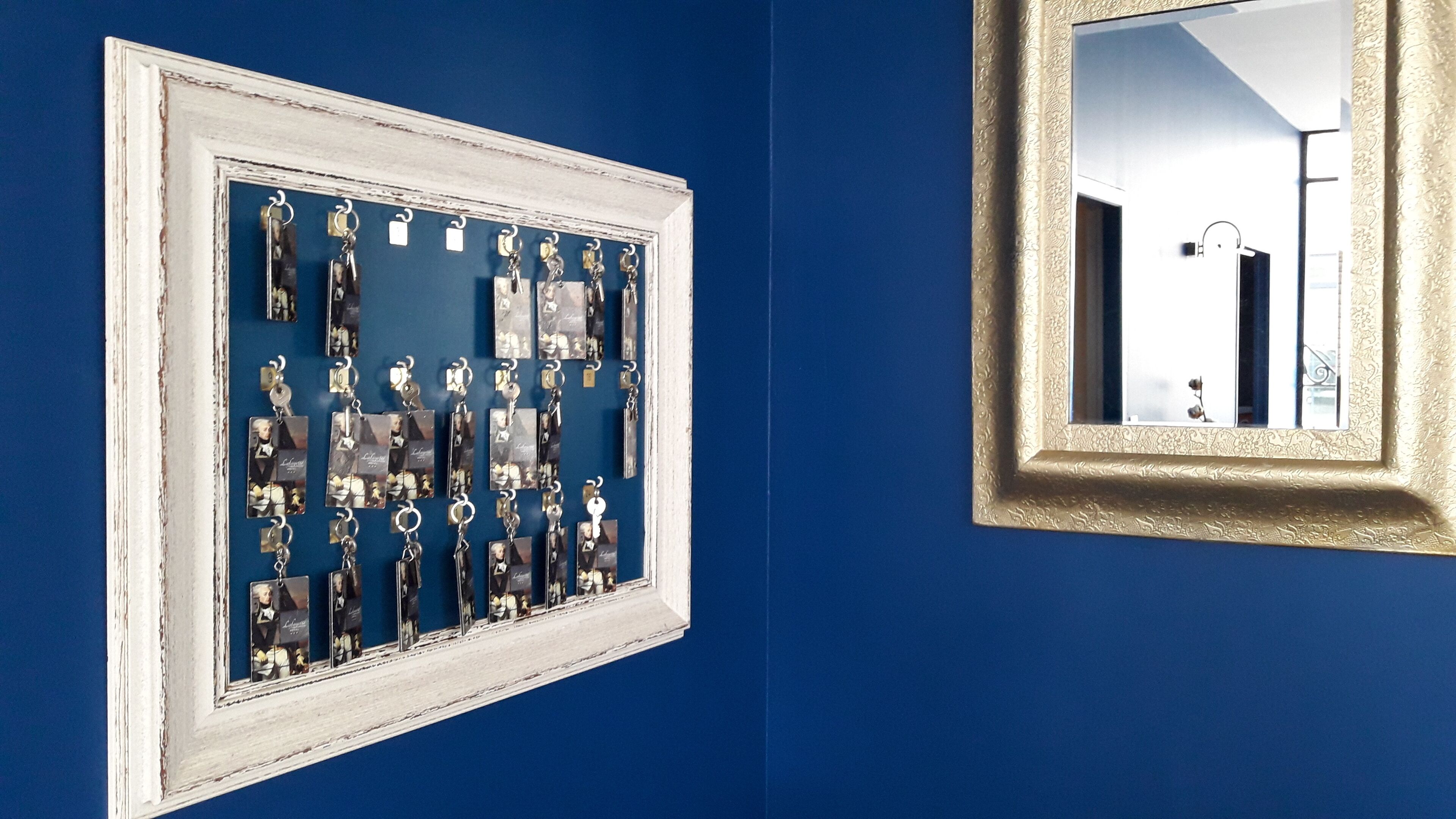 Pareda com fundo azul e quadro em moldura branca.