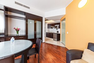 Uma sala de estar moderna com mesa de jantar de vidro, piso de madeira escura e um sofá.