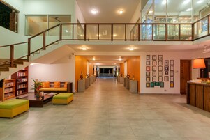 Um amplo hall de hotel com escada, área de estar e uma parede de certificados emoldurados.