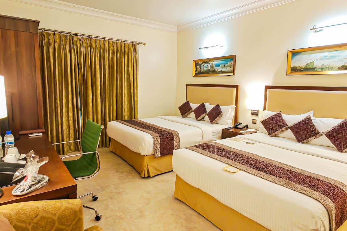 Quarto de hotel com duas camas, uma escrivaninha, uma cadeira e um quadro na parede.