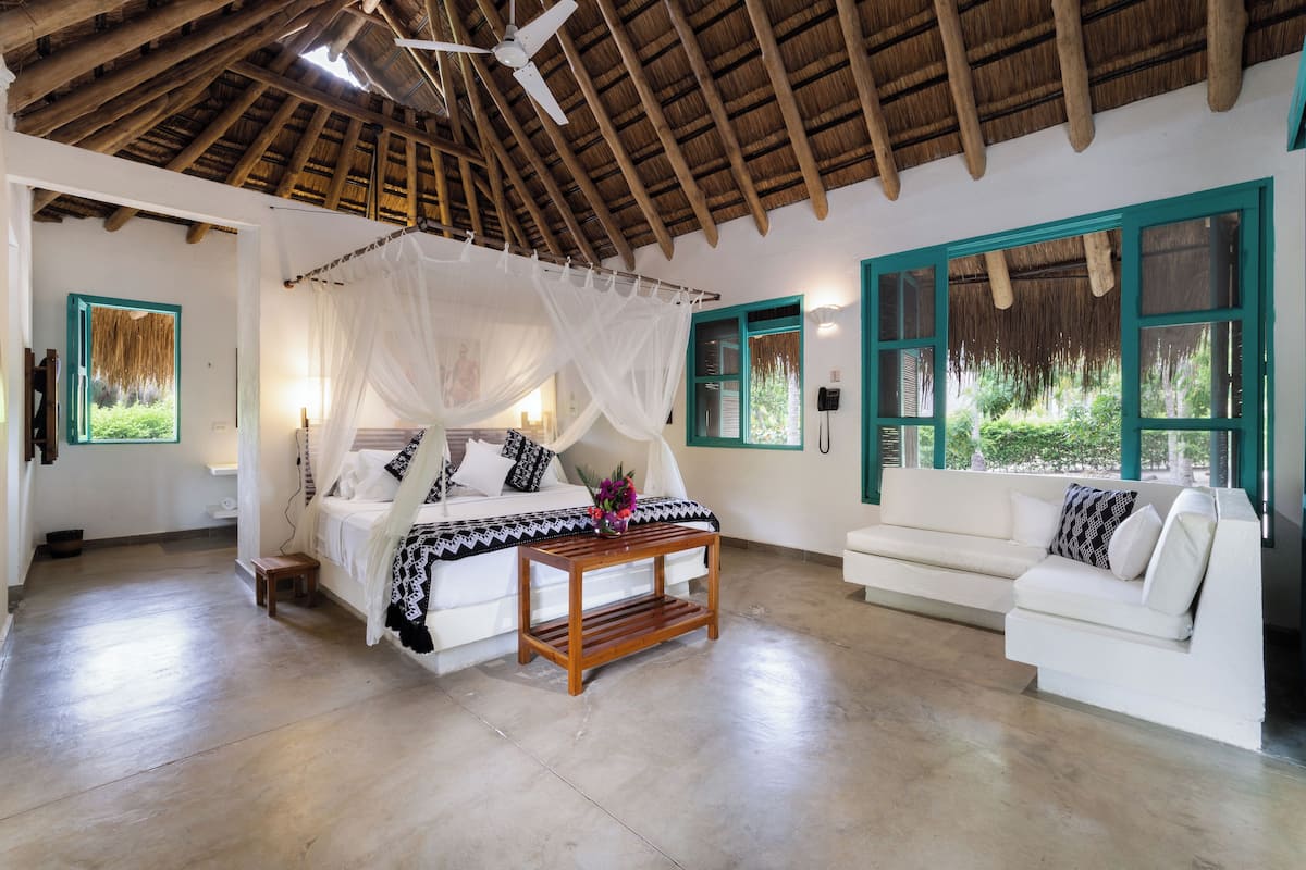 Um quarto com cama, mesa de cabeceira, janela e ventilador de teto.