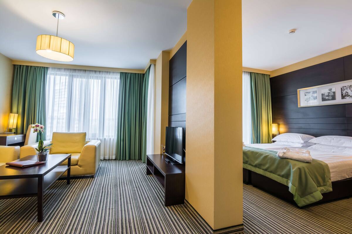 Quarto de hotel com cama, televisão, escrivaninha e cadeira.