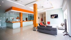 Um lobby de hotel moderno com balcão de recepção, área de estar e televisão de tela plana.
