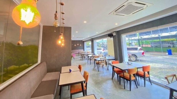 Um restaurante moderno com mesas, cadeiras, uma janela grande e luminárias pendentes.