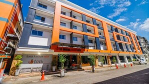 Hotel de vários andares com design moderno, destacando uma paleta de cores laranja e branco.
