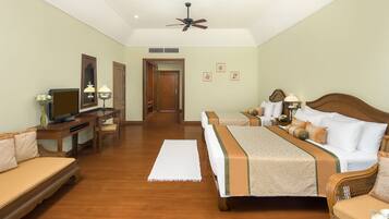 Quarto de hotel com uma cama grande, um sofá, uma televisão e uma escrivaninha com abajur.