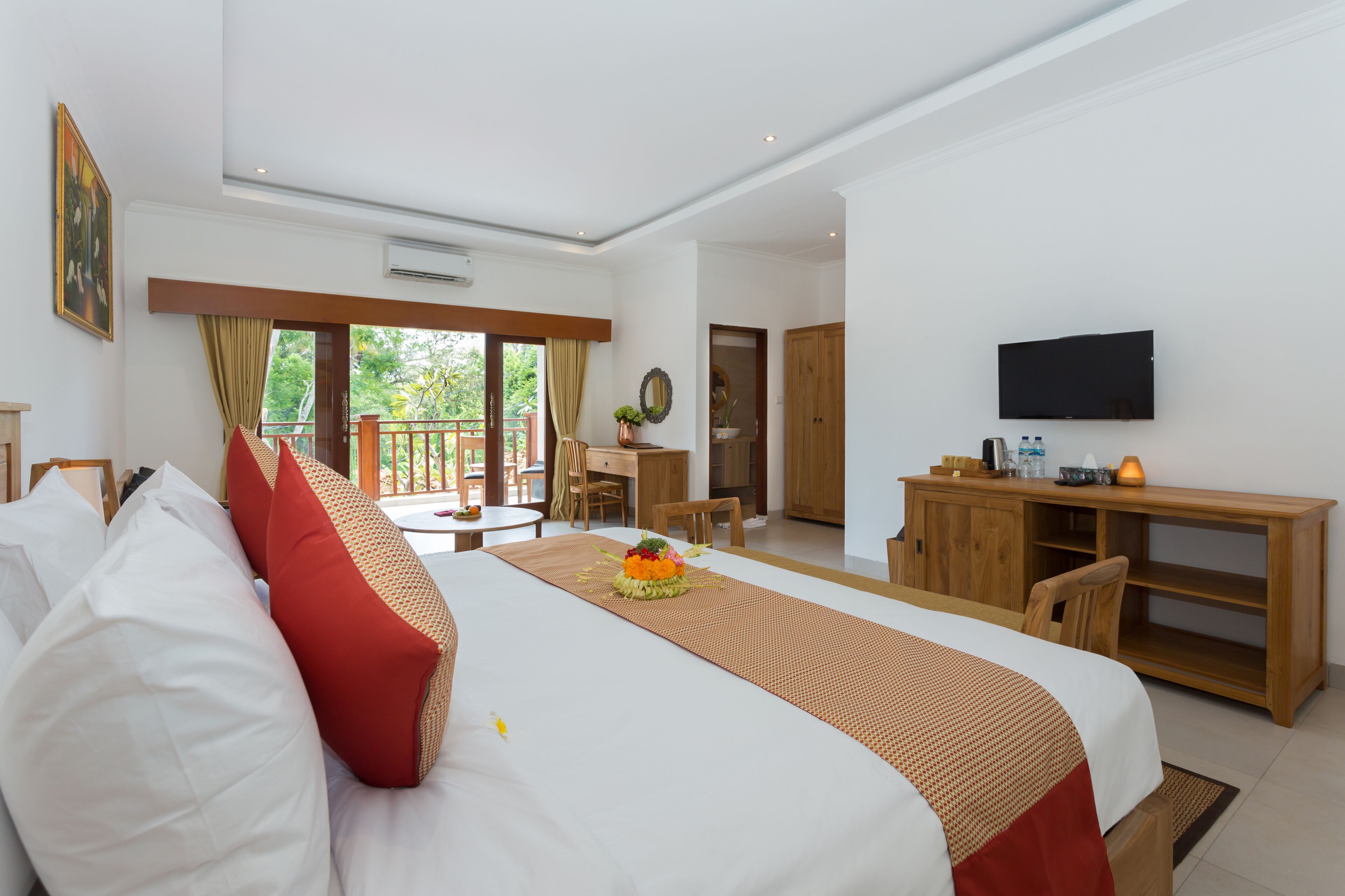 Quarto de hotel com cama, mesa de trabalho, televisão e varanda.