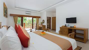 Quarto de hotel com cama, mesa de trabalho, televisão e varanda.