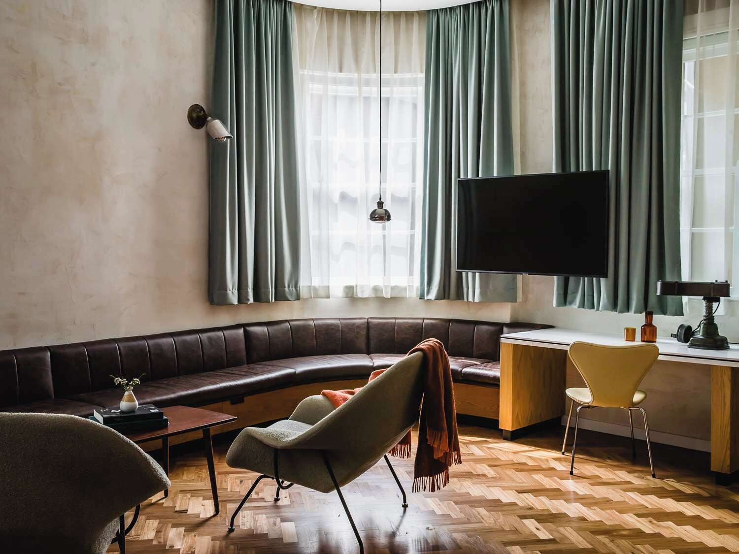 Uma sala de estar moderna com um sofá curvo, uma televisão de tela plana e uma escrivaninha com um computador.