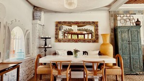 Uma área de refeições com uma mesa branca, cadeiras de madeira, um espelho grande e um armário verde.