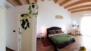 Quarto com cama, mesas de cabeceira, escrivaninha e planta pendente.
