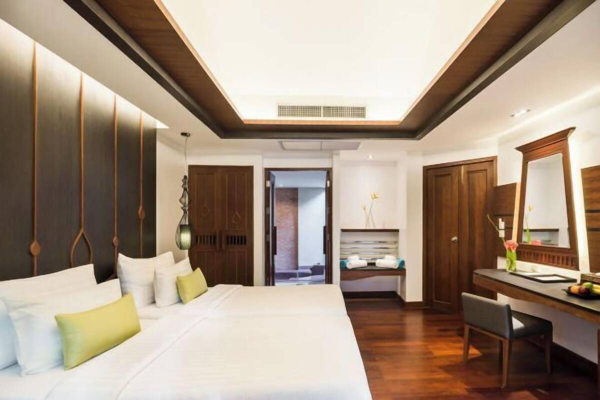 Quarto de hotel com uma cama grande, uma mesa e um espelho.