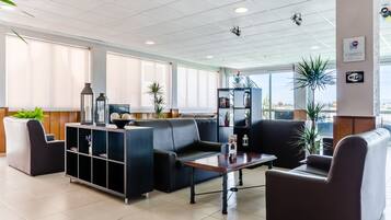 Um lobby moderno com sofás de couro, uma mesa de console preta e plantas em vasos.