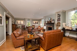 Uma sala de estar espaçosa com sofás de couro, lareira e uma estante cheia de livros e objetos decorativos.
