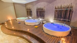Uma área de spa com três banheiras de hidromassagem dispostas em semicírculo, cercada por um deck de madeira e ladrilhos de pedra.