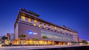 Um hotel moderno com telhado plano, várias varandas e uma grande fachada de vidro.