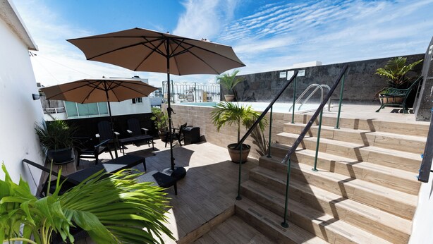 Um terraço no telhado com área de estar ao ar livre, piscina e escadaria.