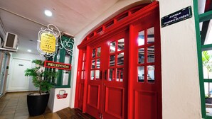 Uma área de recepção de hotel com uma porta vermelha, uma placa de recepção e uma indicação que mostra a localização na Avenida dos Champs-Élysées.